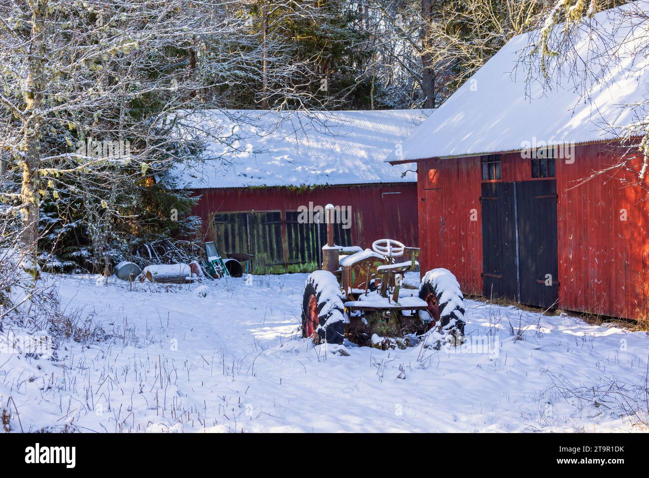 Old tractor by red barns on a cold winter day Stock Photo - Alamy