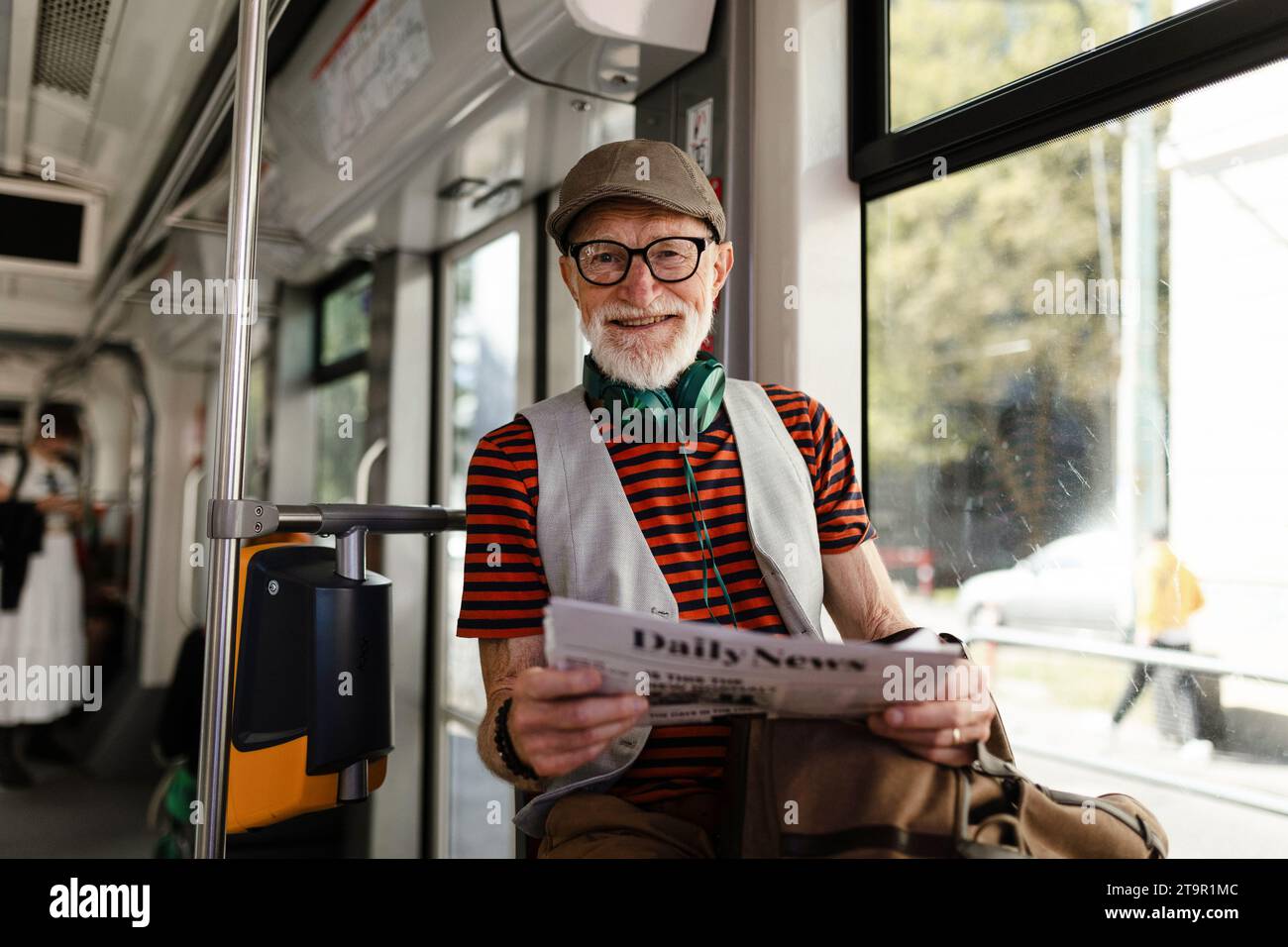 Elderly man traveling through the city by bus, reading newspaper ...