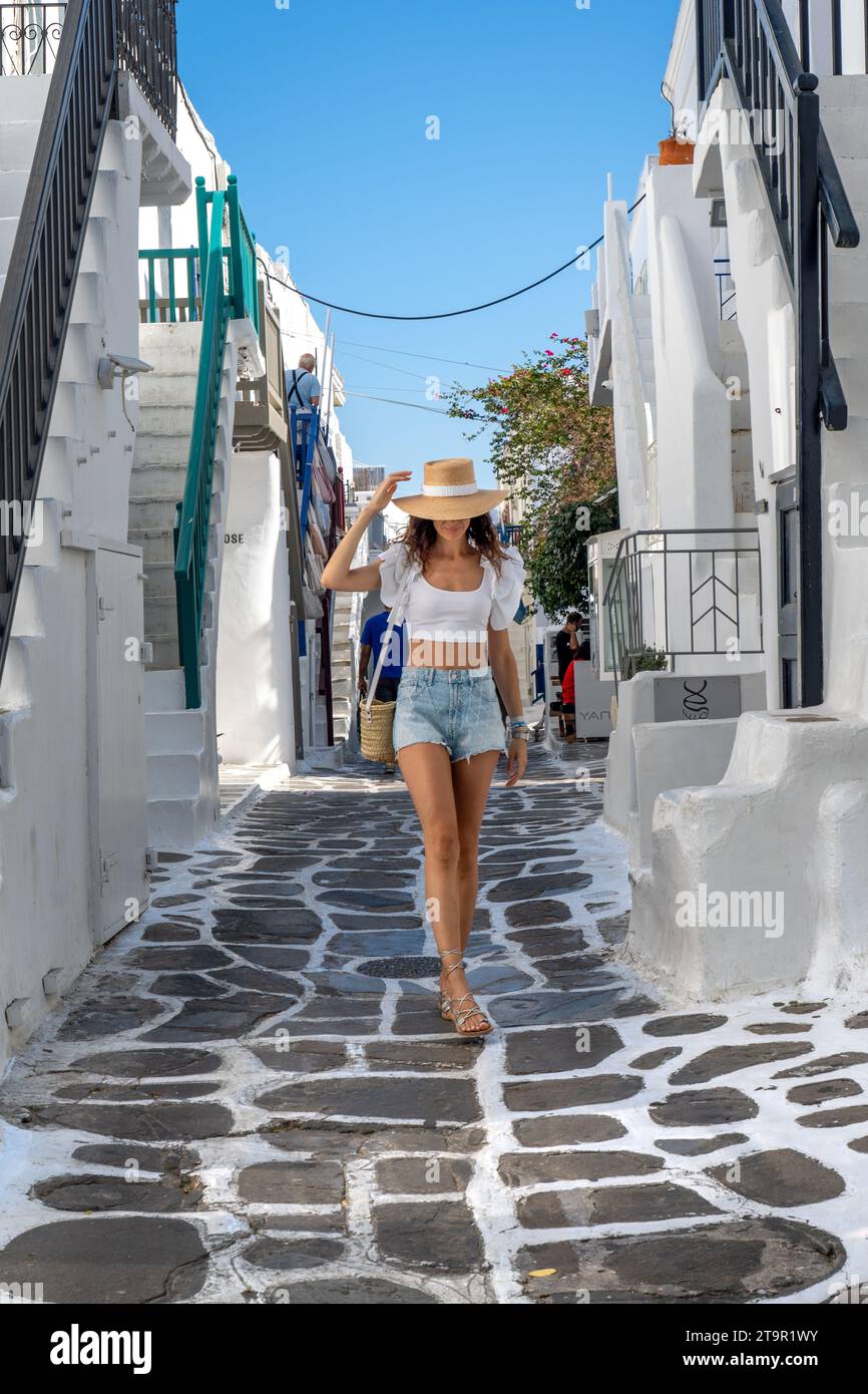 A young woman striding confidently down a quaint cobblestone street ...