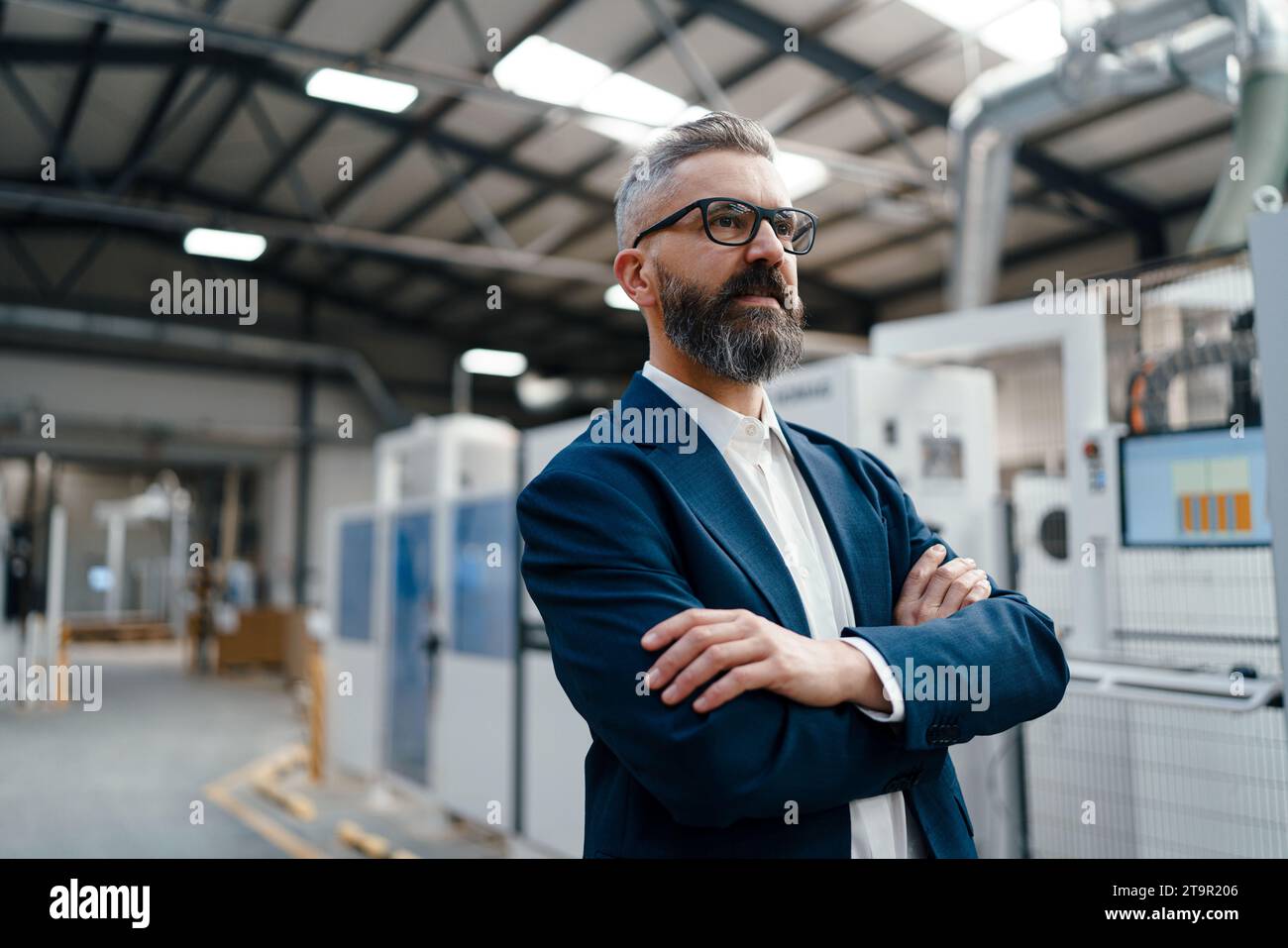 Male project manager standing in modern industrial factory, low angle ...