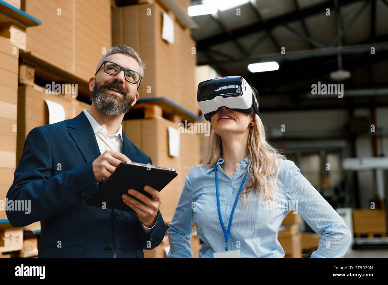 Warehouse managers talking logistics using VR, controlling stock levels ...