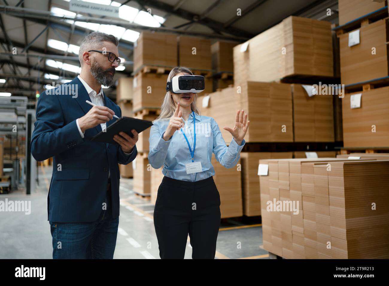 Warehouse managers talking logistics using VR, controlling stock levels ...