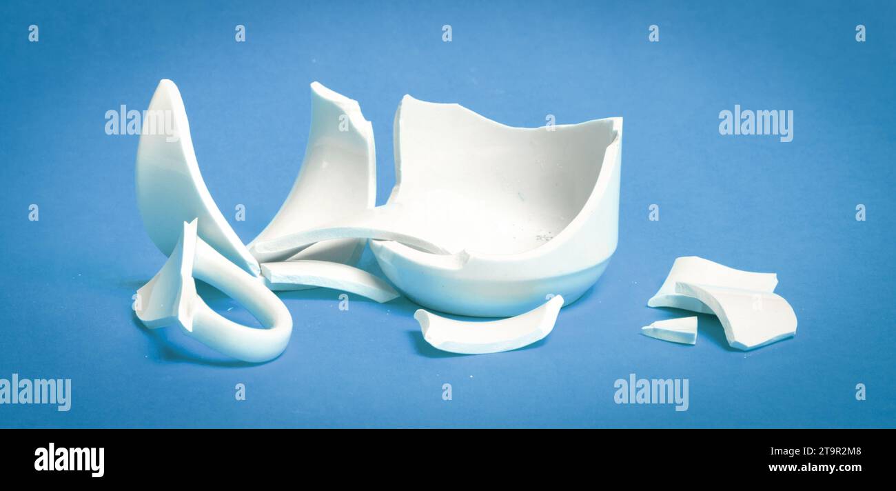 Broken cup isolated on a solid blue background Stock Photo - Alamy