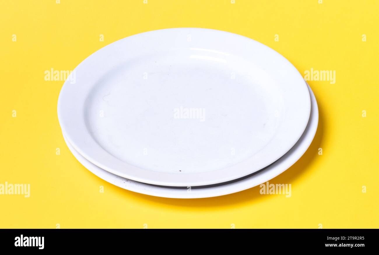 Two white plates on a solid yellow background Stock Photo - Alamy