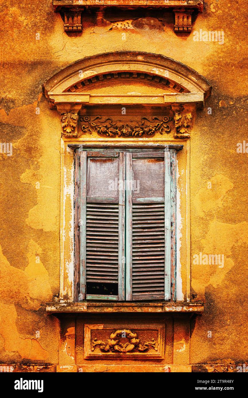 Old window with wooden shutters, ruined yellow facade with worn surface ...