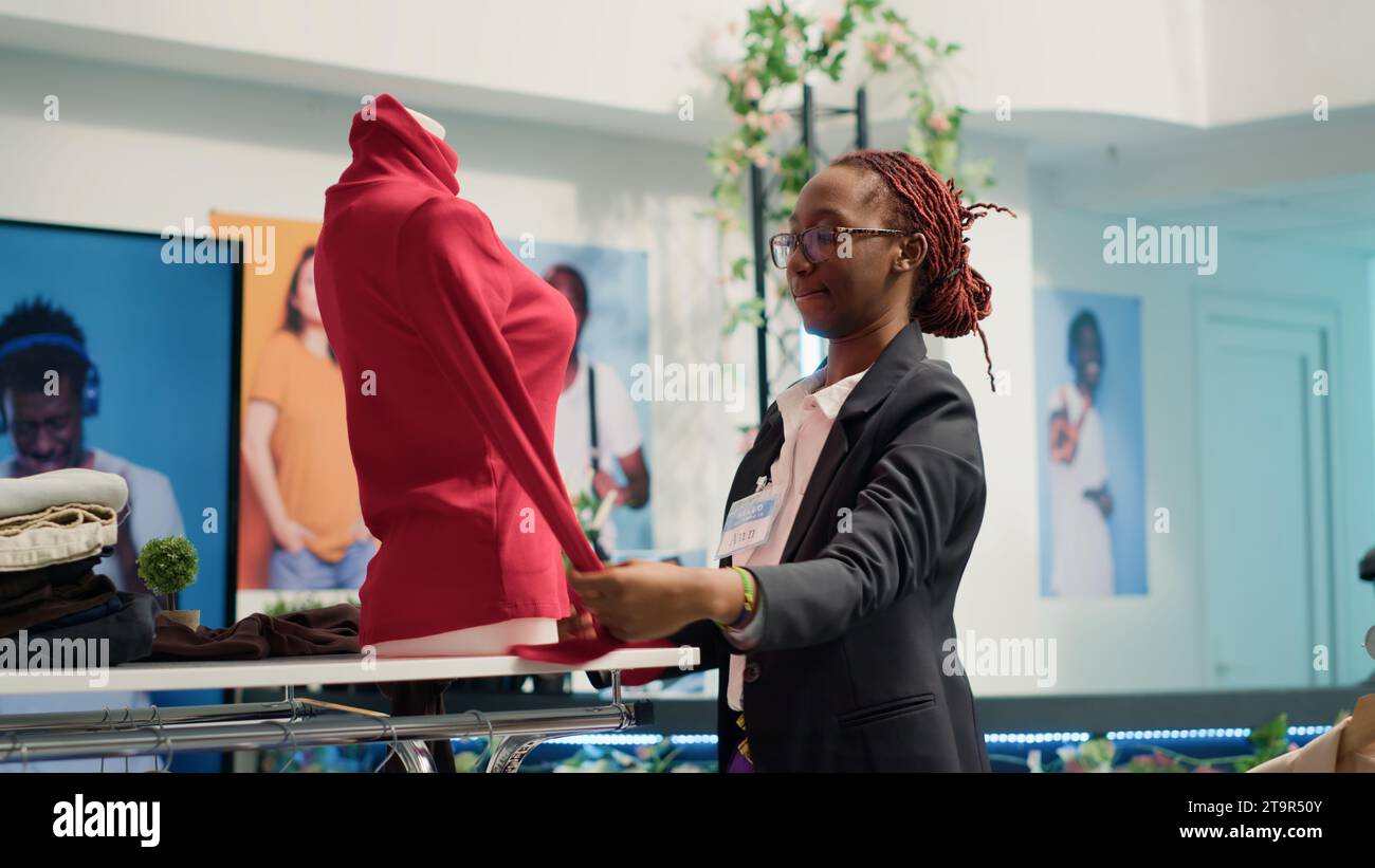 Meticulous retail assistant working in luxury fashion boutique, putting ...