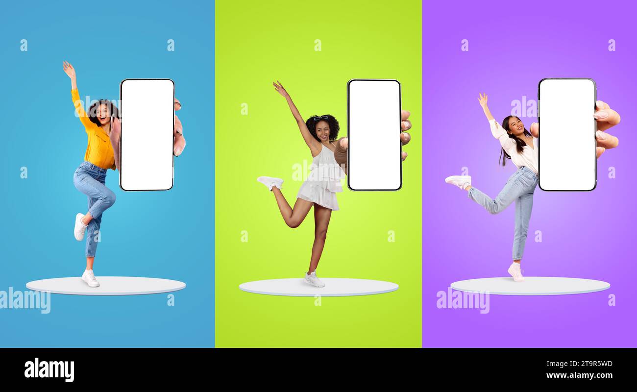Cheerful young international women enjoy win, show big phone with empty ...