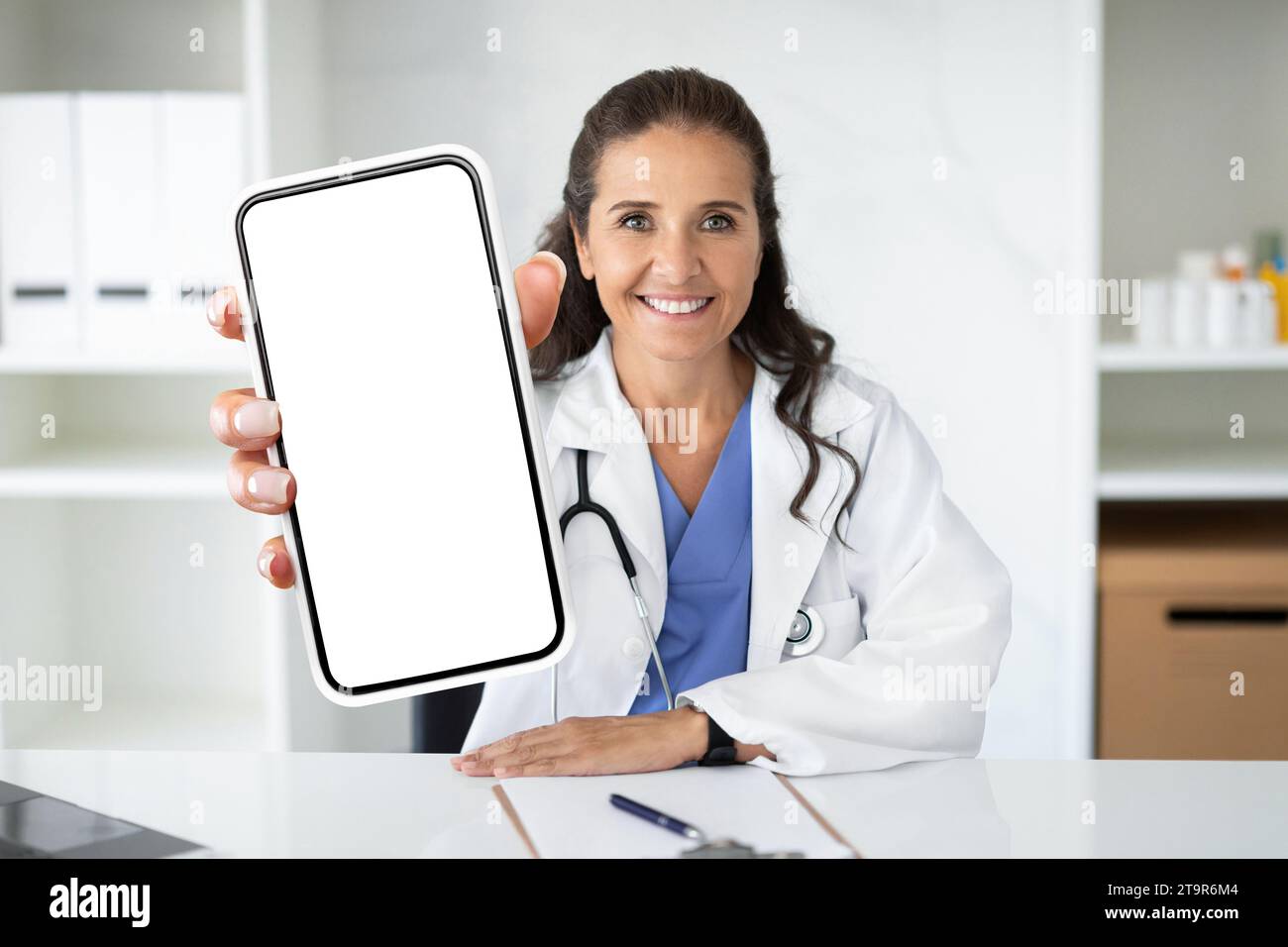Smiling Doctor Lady Holding Smartphone With Blank Screen In Office ...
