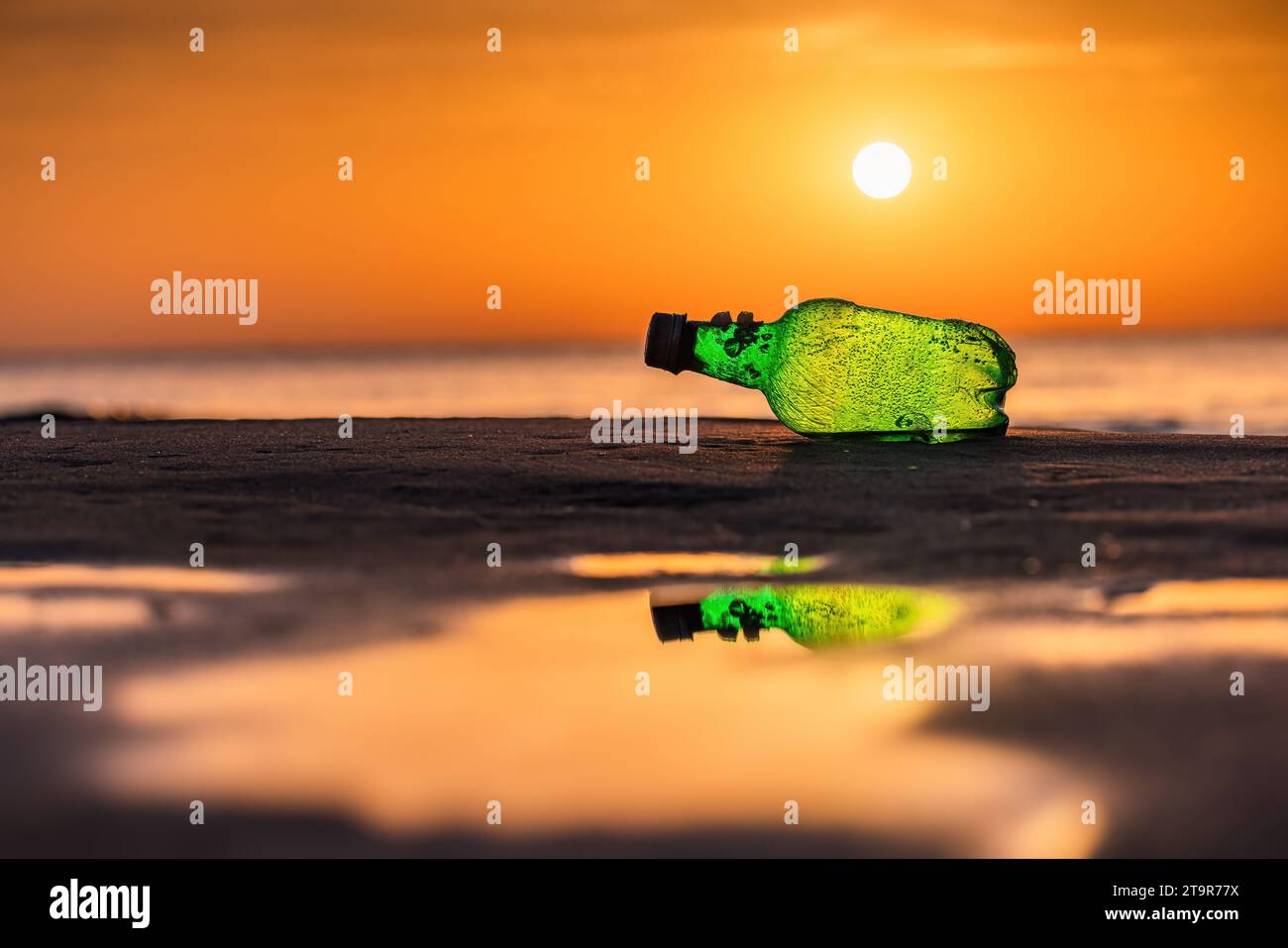 Sea sunrise and plastic alcohol bottle on the beach sand and splashing ...