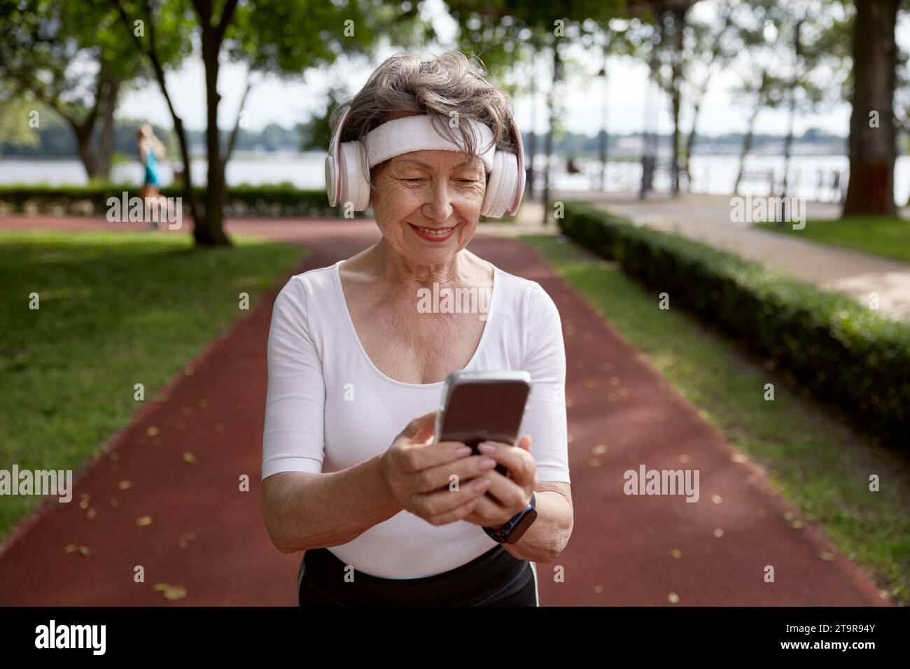Elderly woman using mobile phone during running exercise outdoors Stock ...