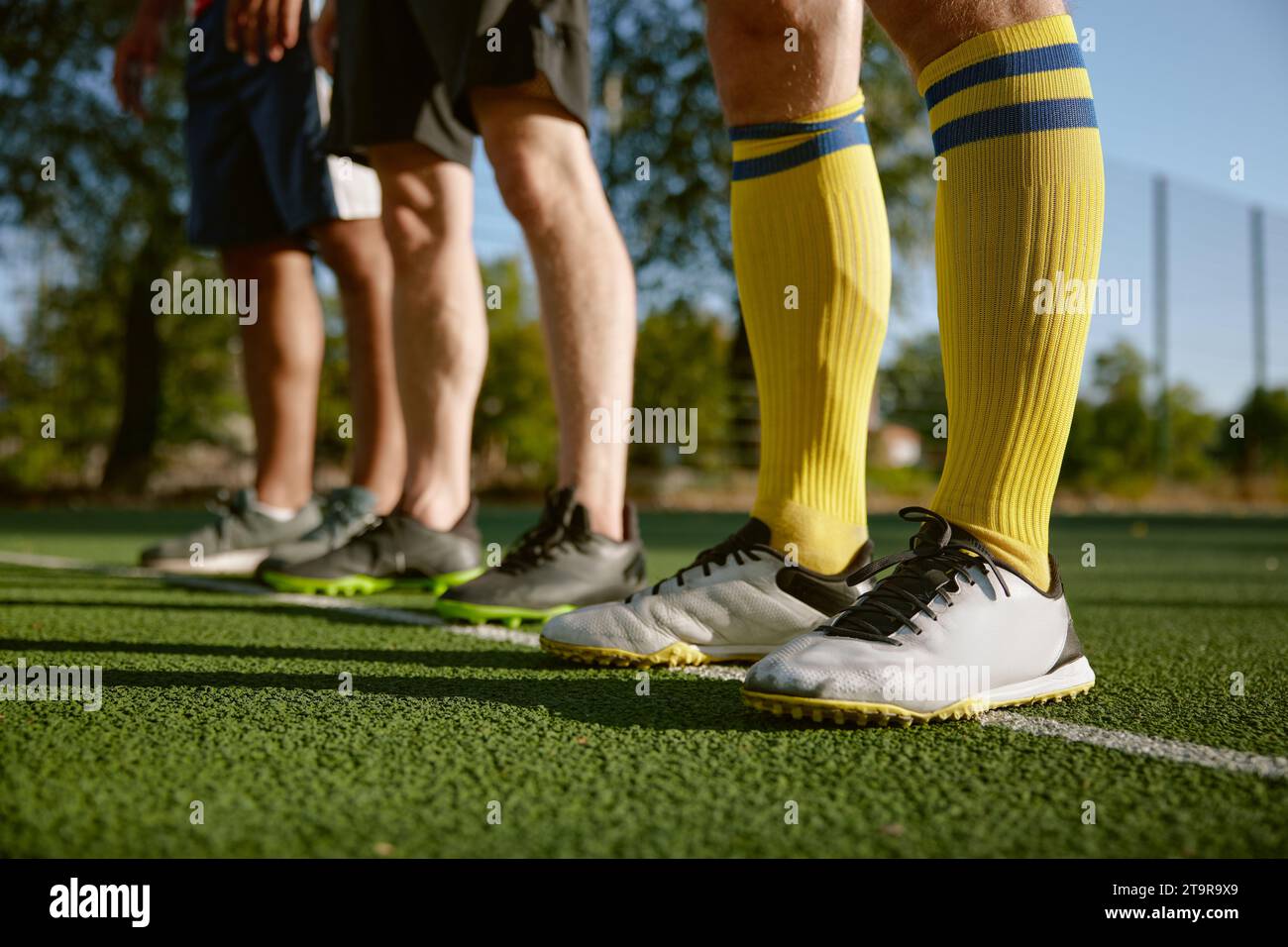 Football player legs standing on white line dividing football field ...