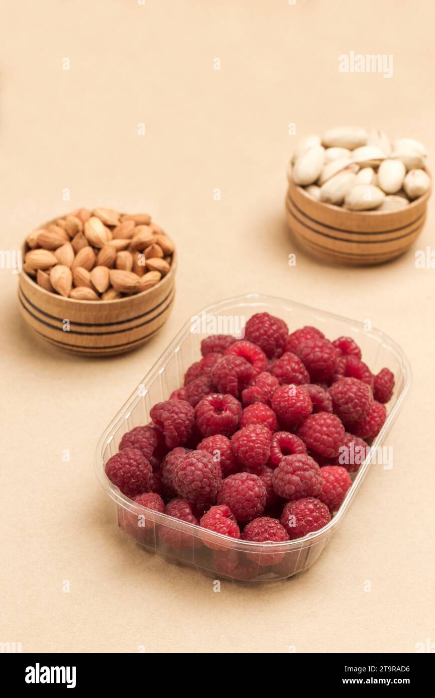 Raspberries and walnuts in plastic containers. Nuts in wooden boxes ...