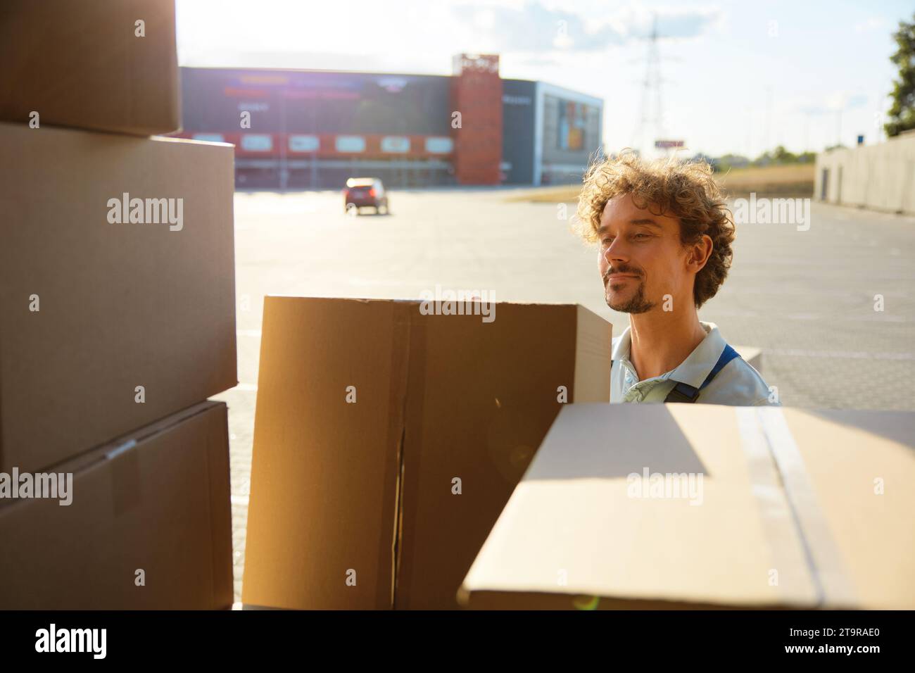 Young warehouse worker holding clipboard box unloading delivery truck ...
