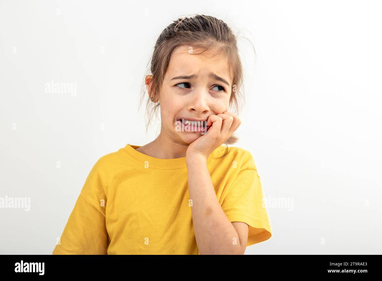 Scared and anxious girl, biting her fingernails on a white background ...