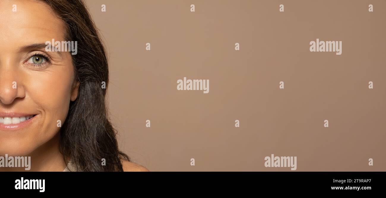 Glad caucasian senior lady enjoy skin care, isolated on beige studio ...