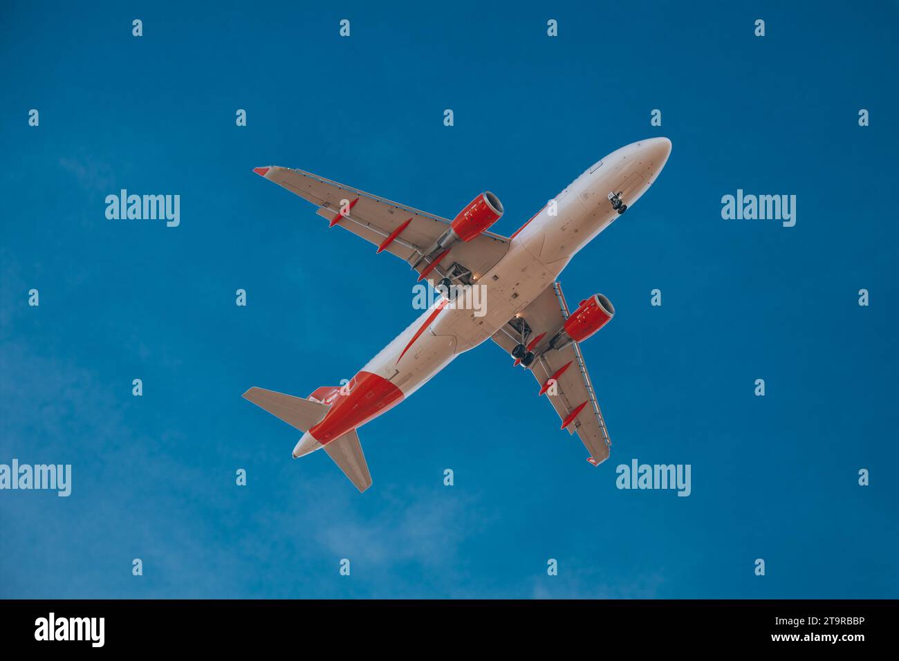 White-red airplane in the sky, bottom view. Airplane landing Stock ...