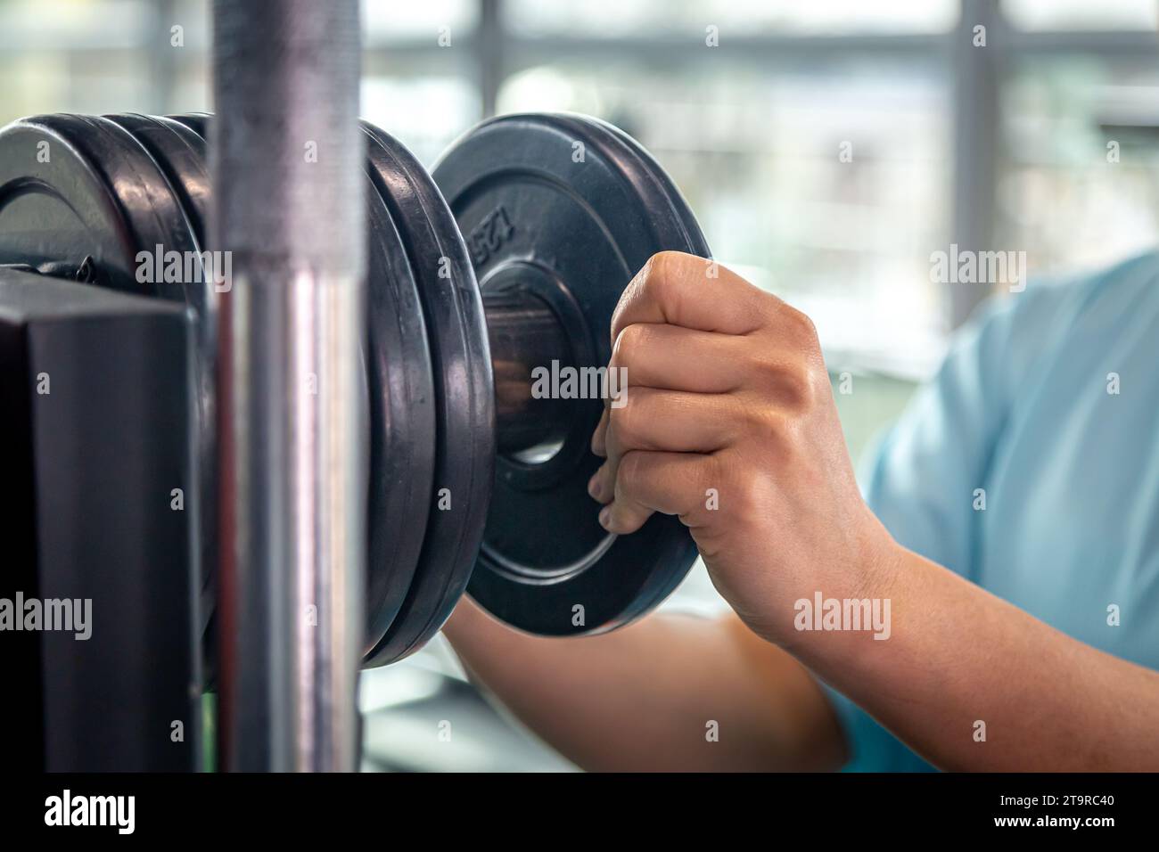 A muscular sportswoman putting weight plates in a gym for bodybuilding ...