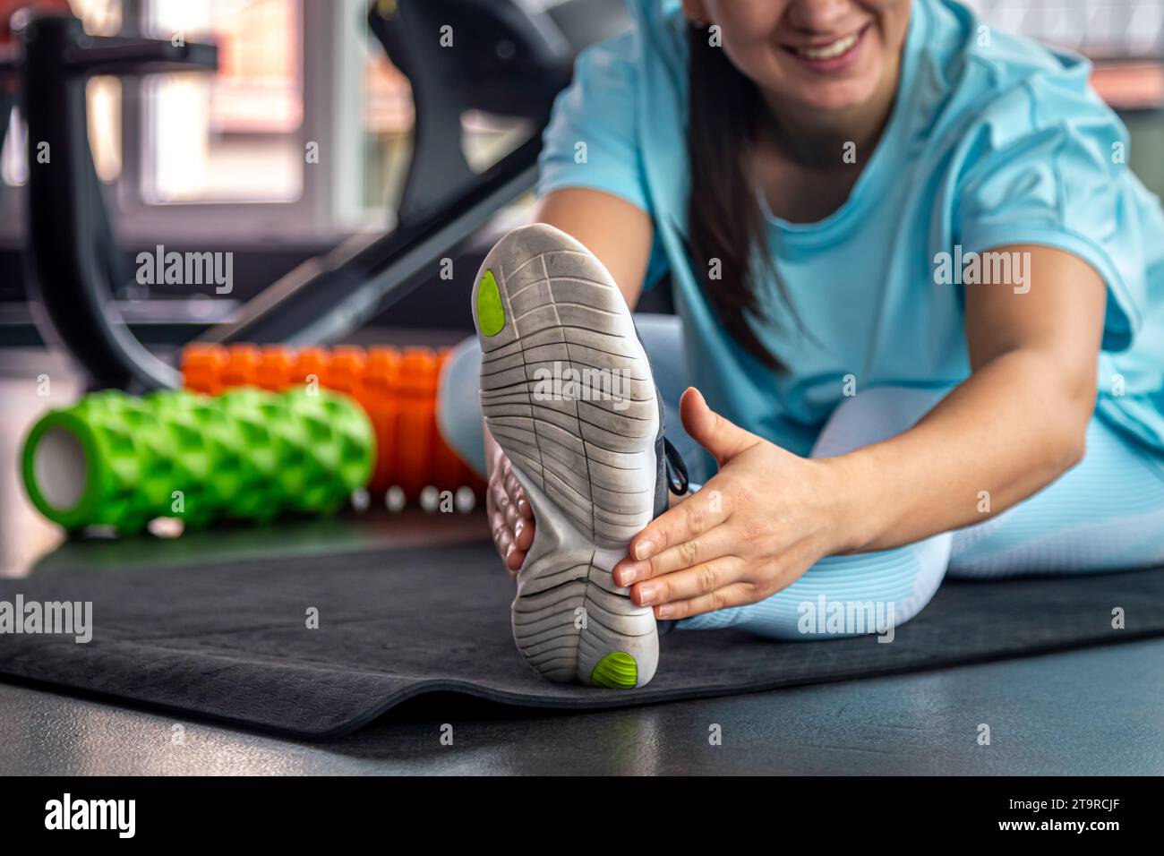Woman stretching legs on exercise mat before training at gym Stock ...