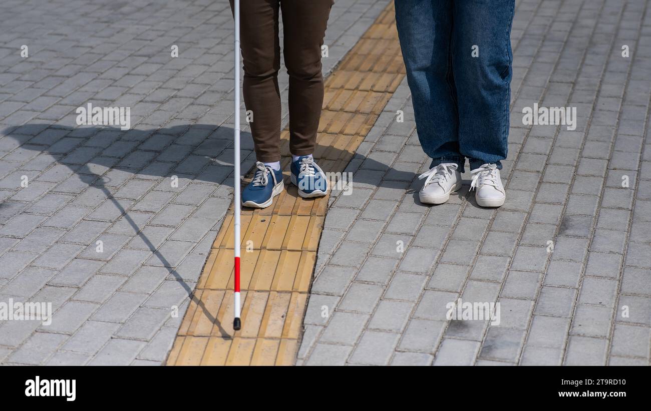 Close-up of a woman's legs accompanying a blind elderly lady outdoors ...