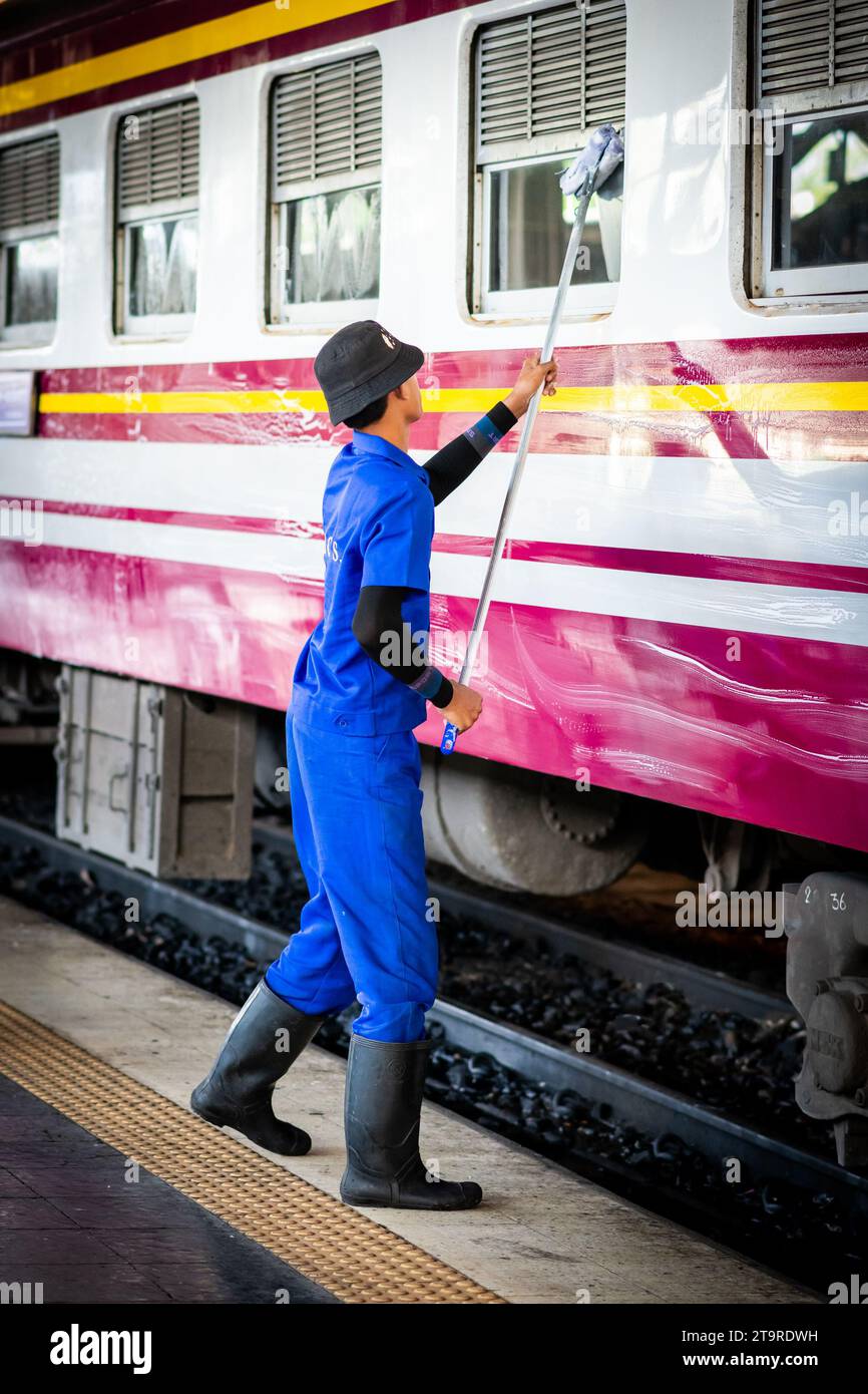 A Thai cleaner makes his way along the side of a train carriage ...