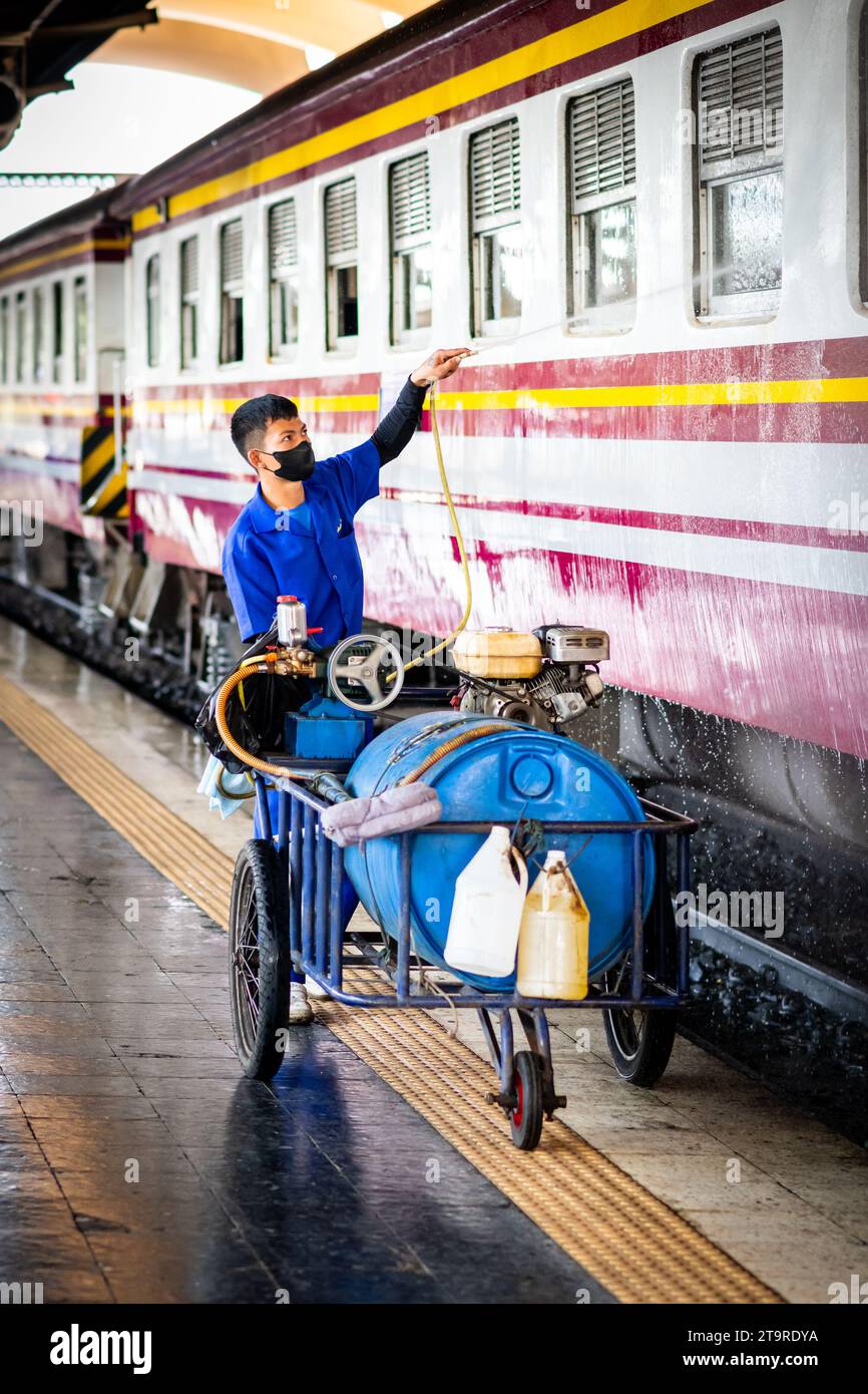 A Thai cleaner makes his way along the side of a train carriage ...