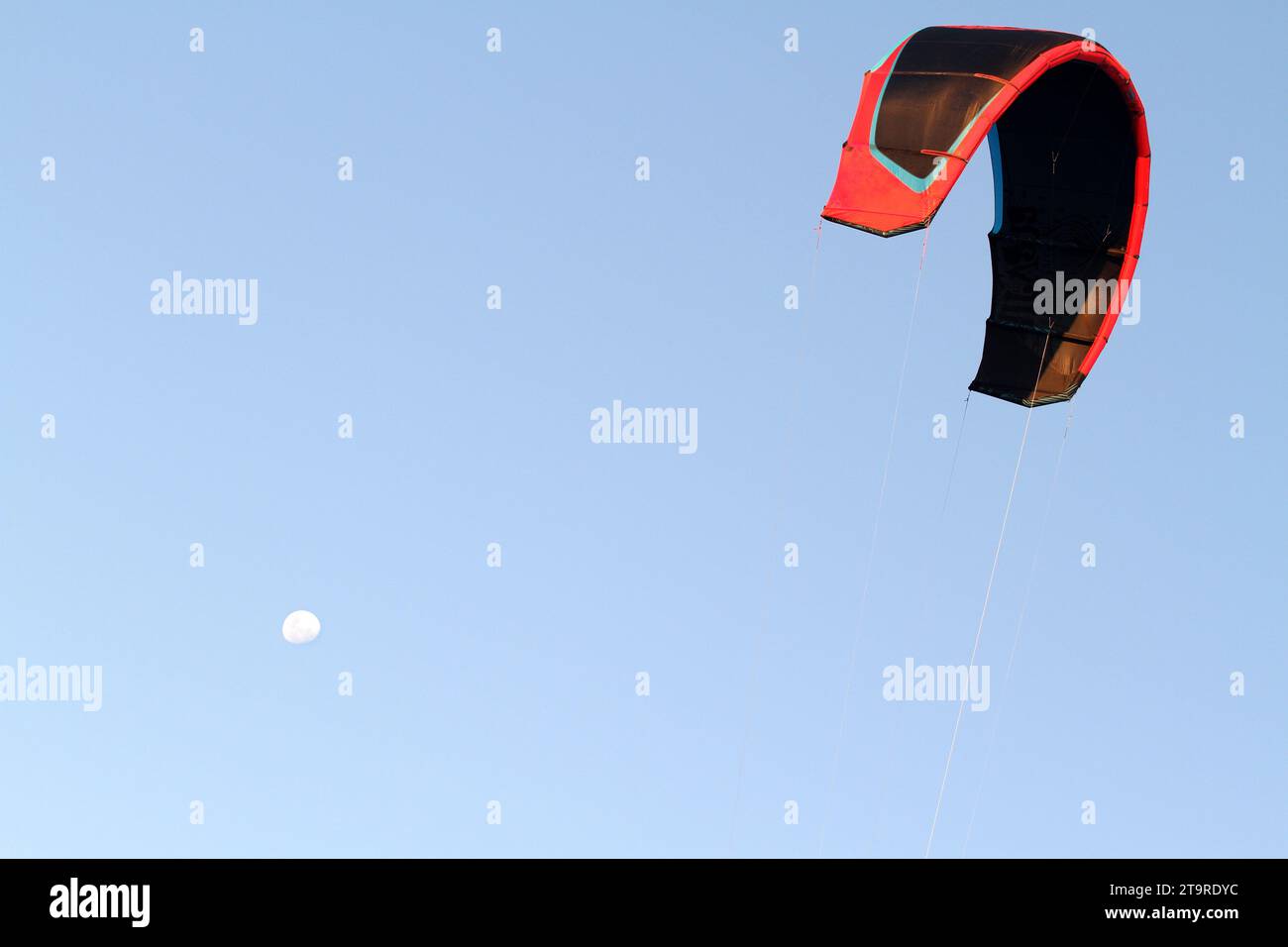 A kitesurfer's inflatable kite can be seen against a blue sky with the ...