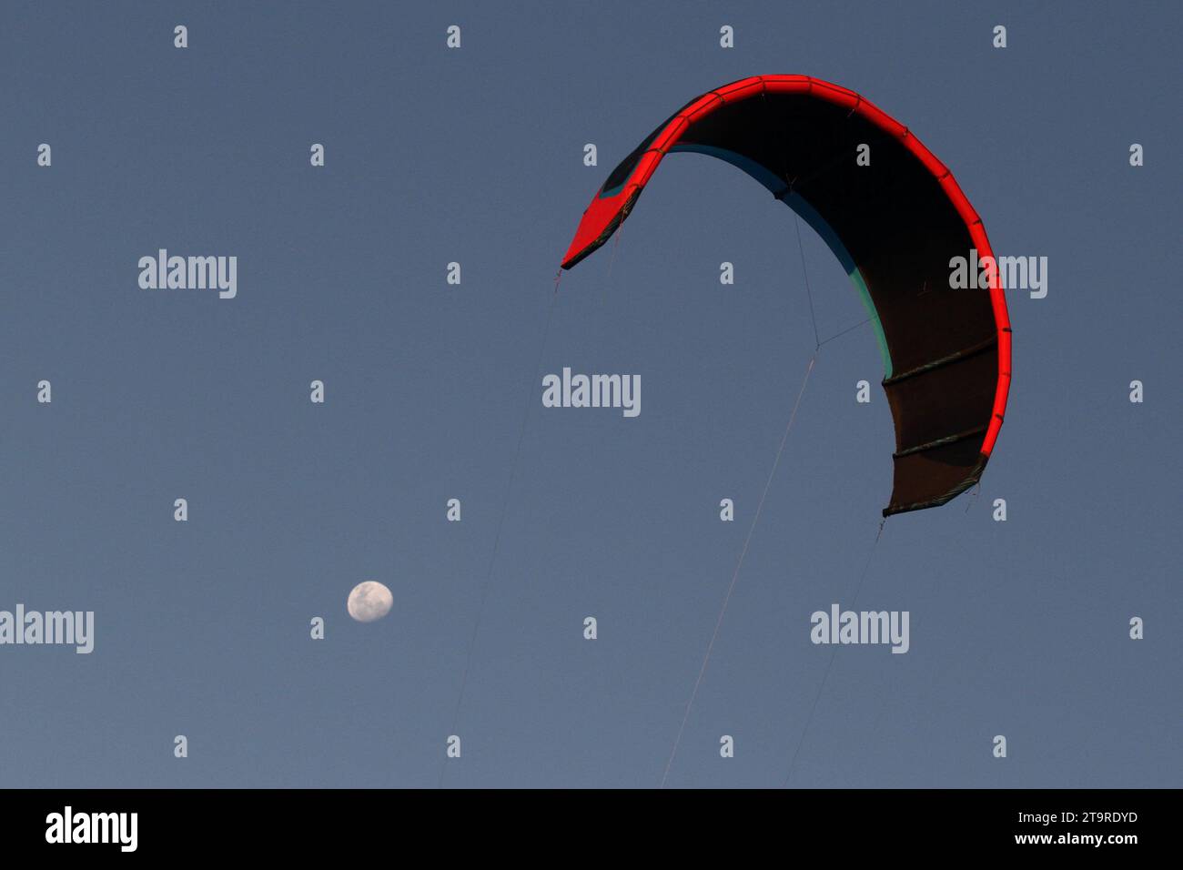 An inflatable kite can be seen against a blue sky with the moon in the ...