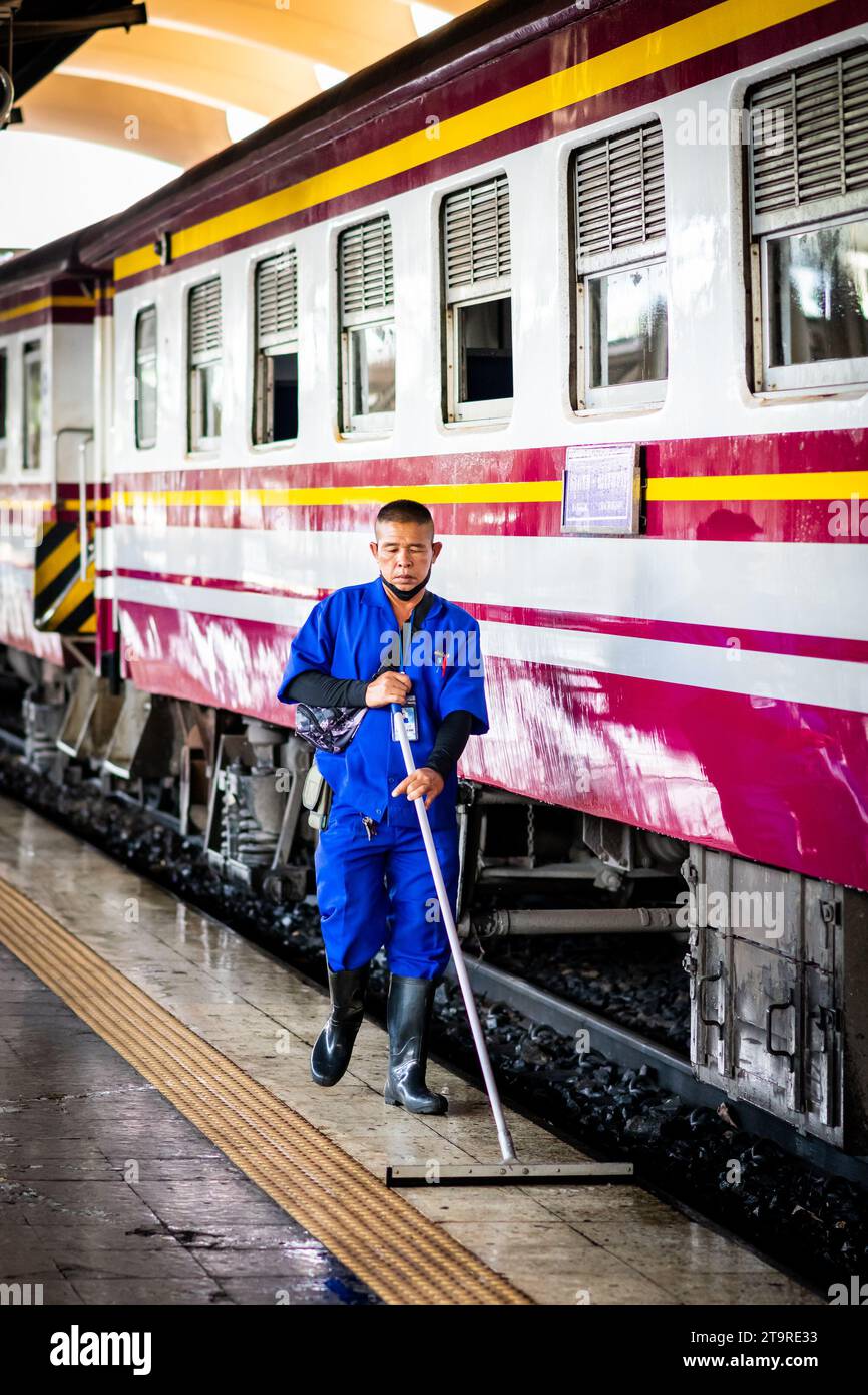A Thai cleaner makes his way along the platform mopping and sweeping ...
