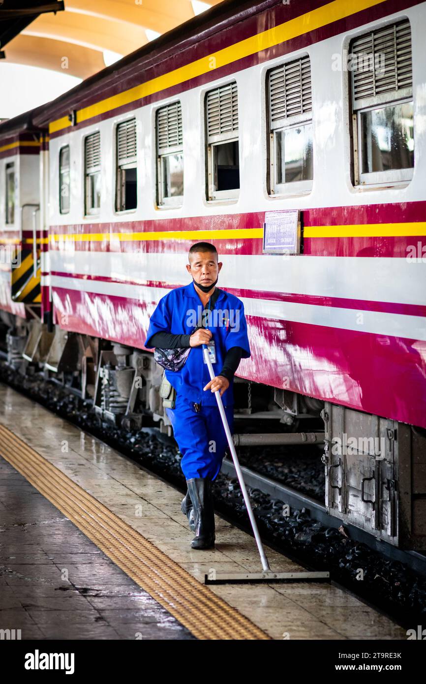 A Thai cleaner makes his way along the platform mopping and sweeping ...