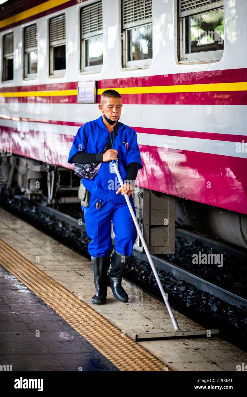 A Thai cleaner makes his way along the platform mopping and sweeping ...