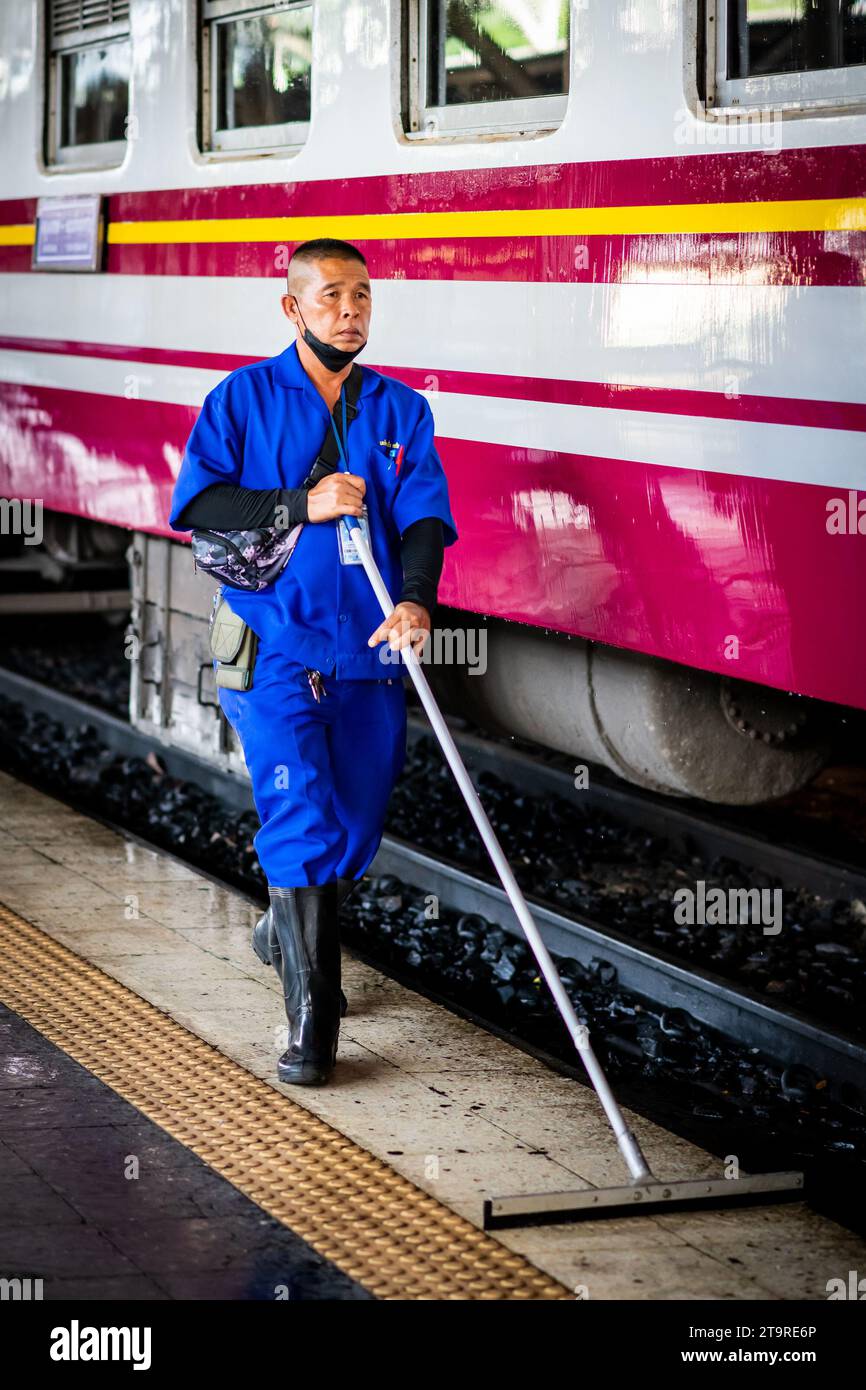 A Thai cleaner makes his way along the platform mopping and sweeping ...