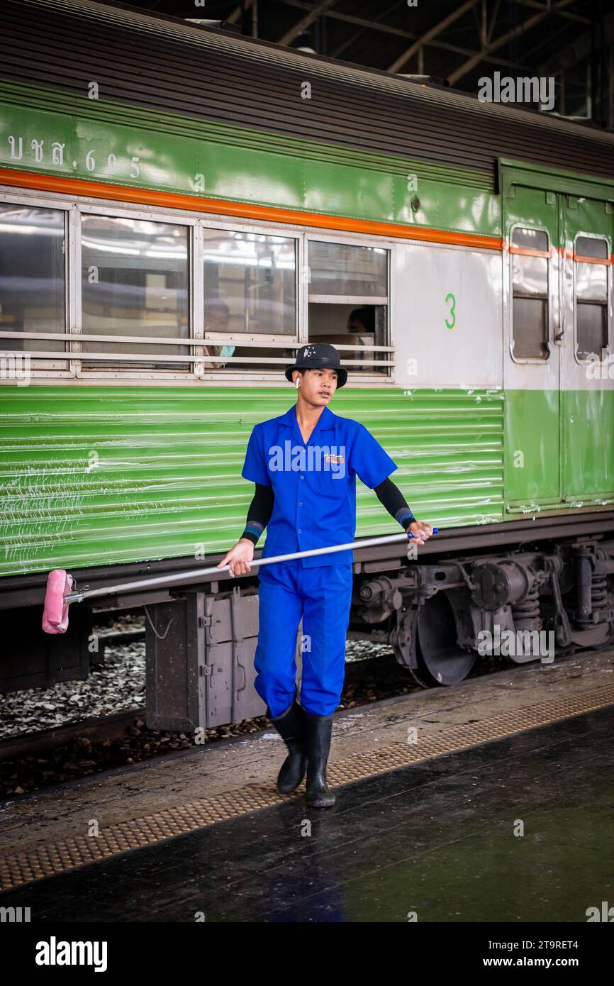 A Thai cleaner makes his way along the side of a train carriage ...