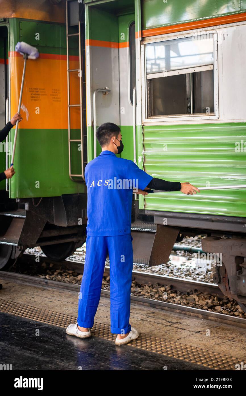 A Thai cleaner makes his way along the side of a train carriage ...