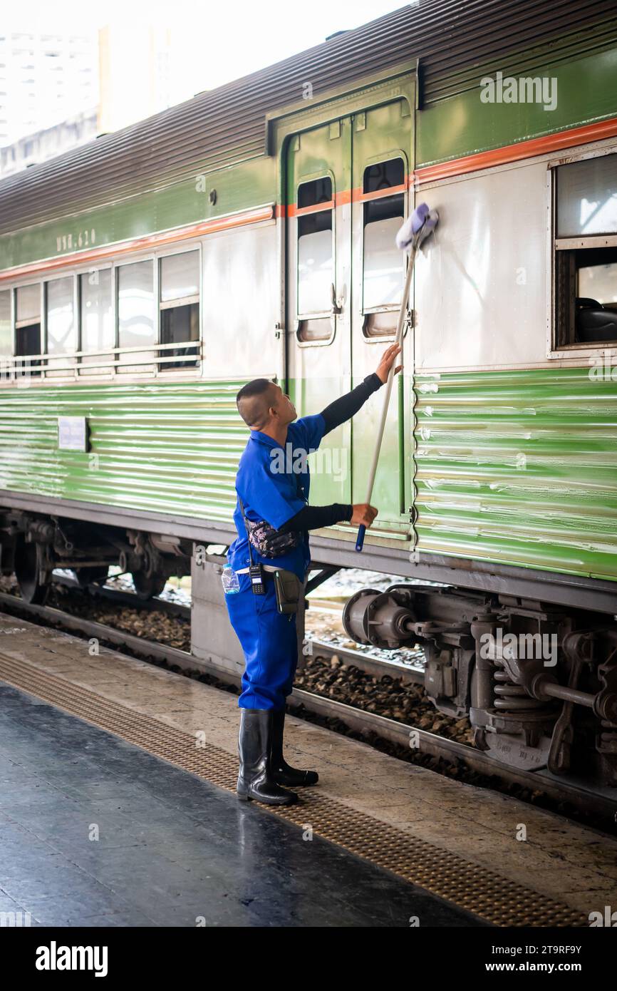 A Thai cleaner makes his way along the side of a train carriage ...