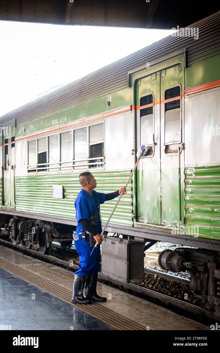 A Thai cleaner makes his way along the side of a train carriage ...