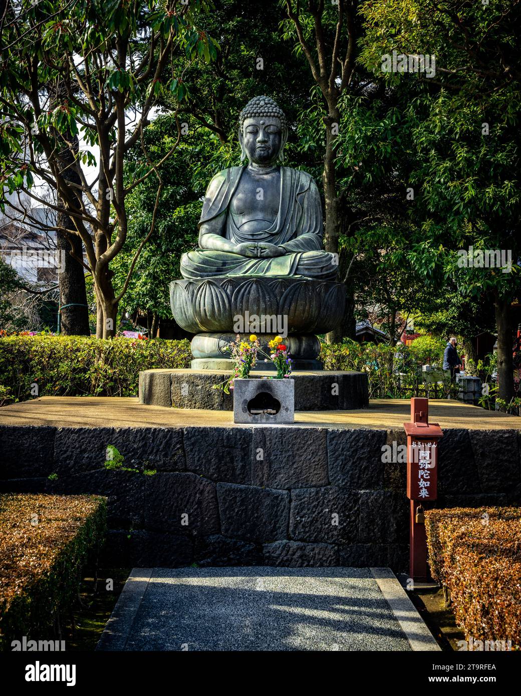 An Ornate Japanese Buddhist Buddha statue shrine with greenery in urban ...