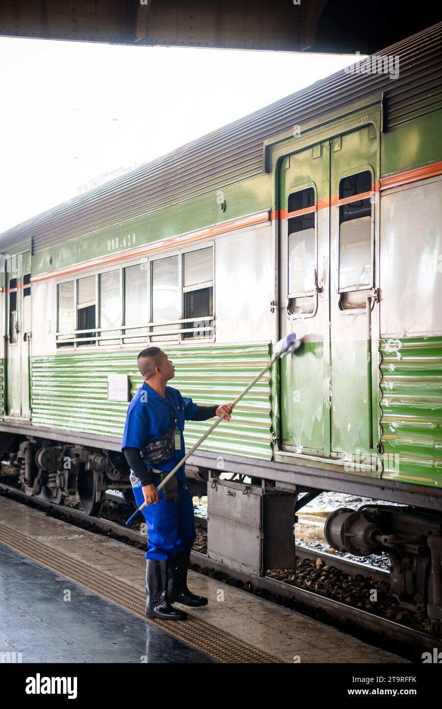 A Thai cleaner makes his way along the side of a train carriage ...