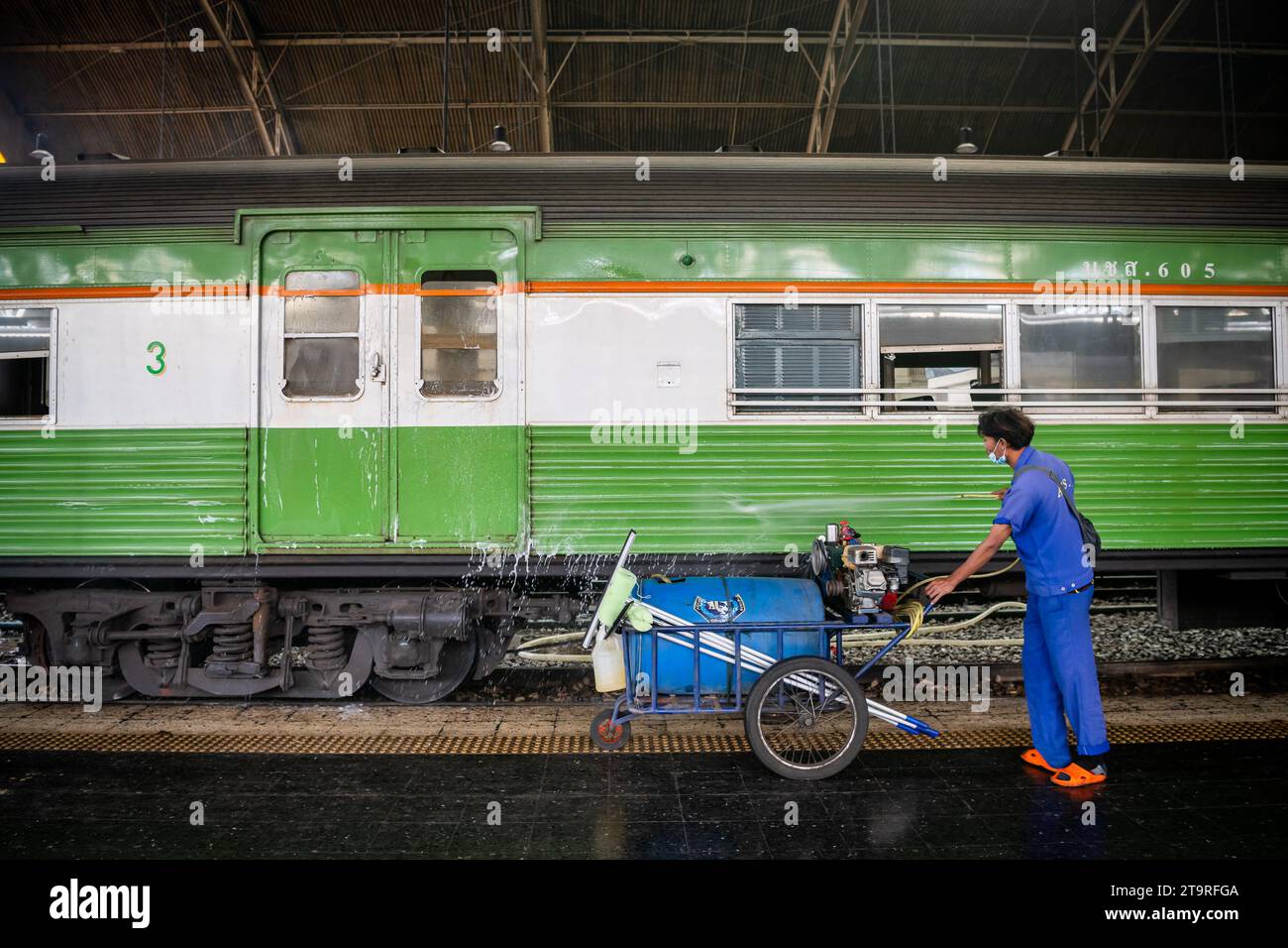A Thai cleaner makes his way along the side of a train carriage ...