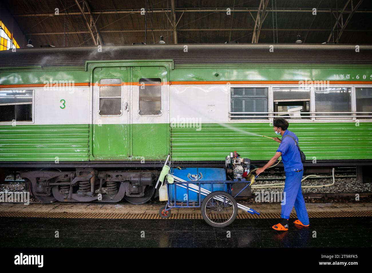 A Thai cleaner makes his way along the side of a train carriage ...