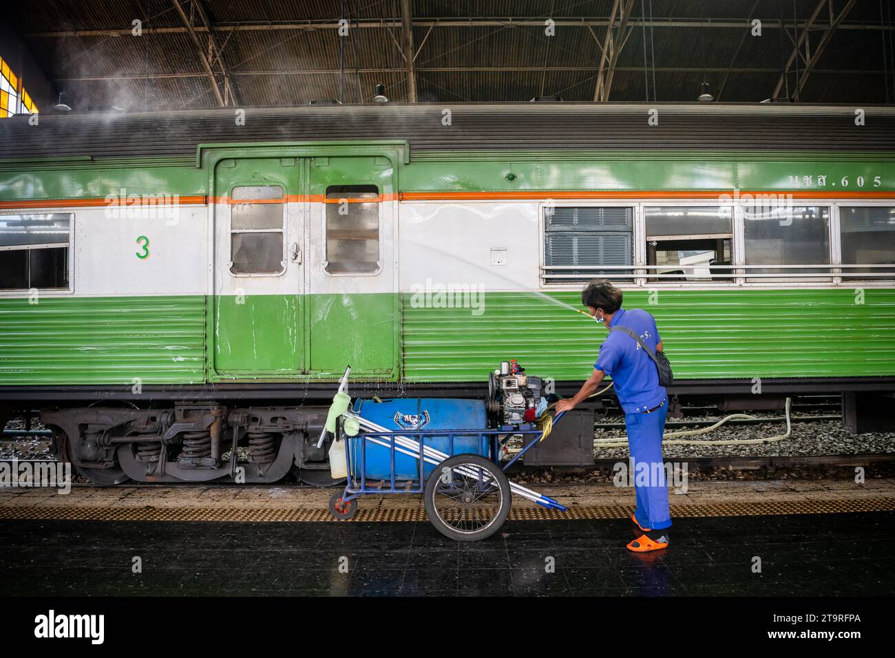 A Thai cleaner makes his way along the side of a train carriage ...