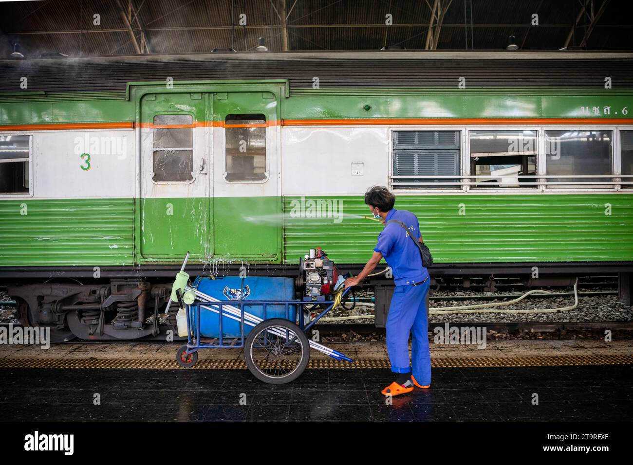 A Thai cleaner makes his way along the side of a train carriage ...
