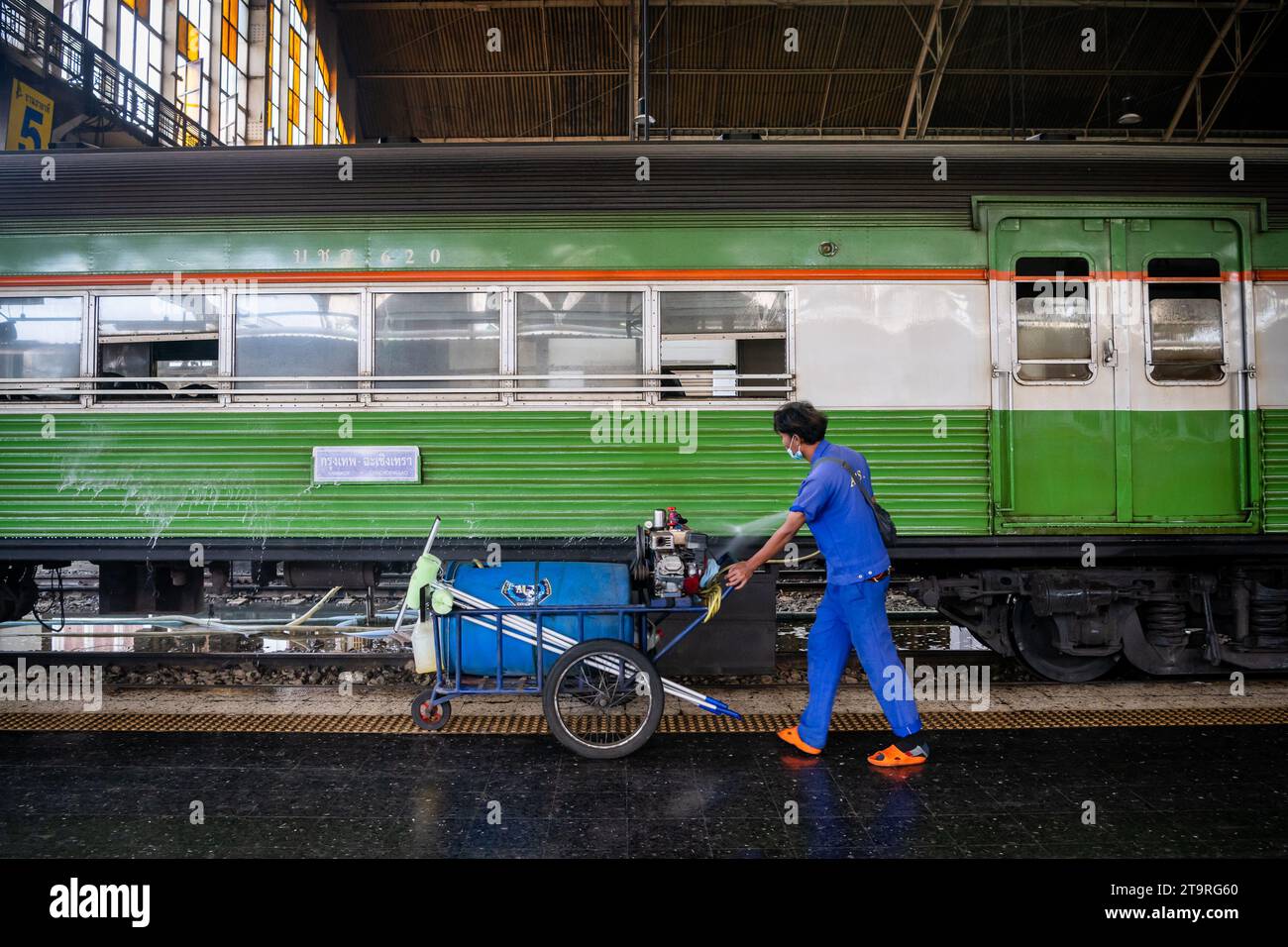 A Thai cleaner makes his way along the side of a train carriage ...