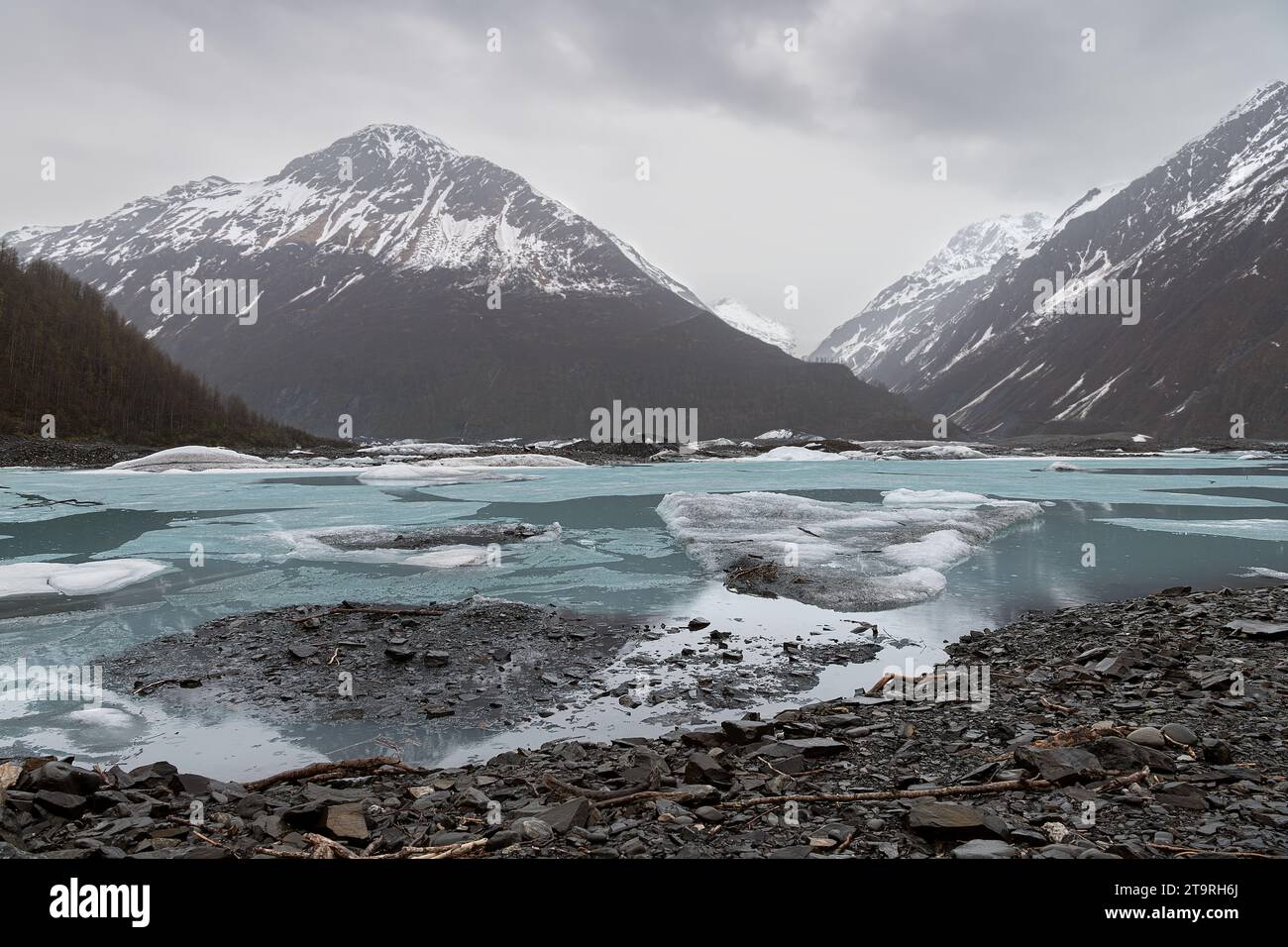 Ice sheets on Valdez Glacier Lake with distance mountains in rain and ...