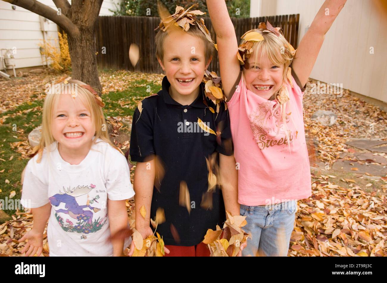 Three kids, two girls and one boy, play in the fall leaves in Fort ...