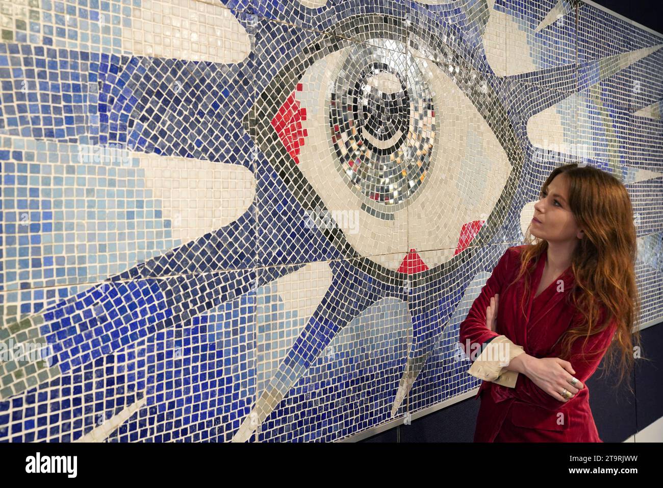 A member of staff looks at John Lennon's psychedelic eye mosaic ...