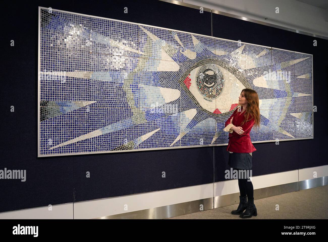 A member of staff looks at John Lennon's psychedelic eye mosaic ...