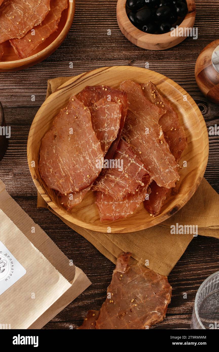 Slices of dried pork on a wooden plate. beer appetizer Stock Photo - Alamy