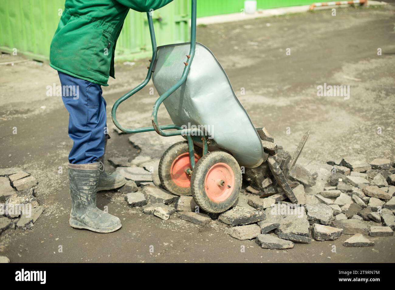 Builder removes broken stone. Man carries cobblestones in cart Stock ...