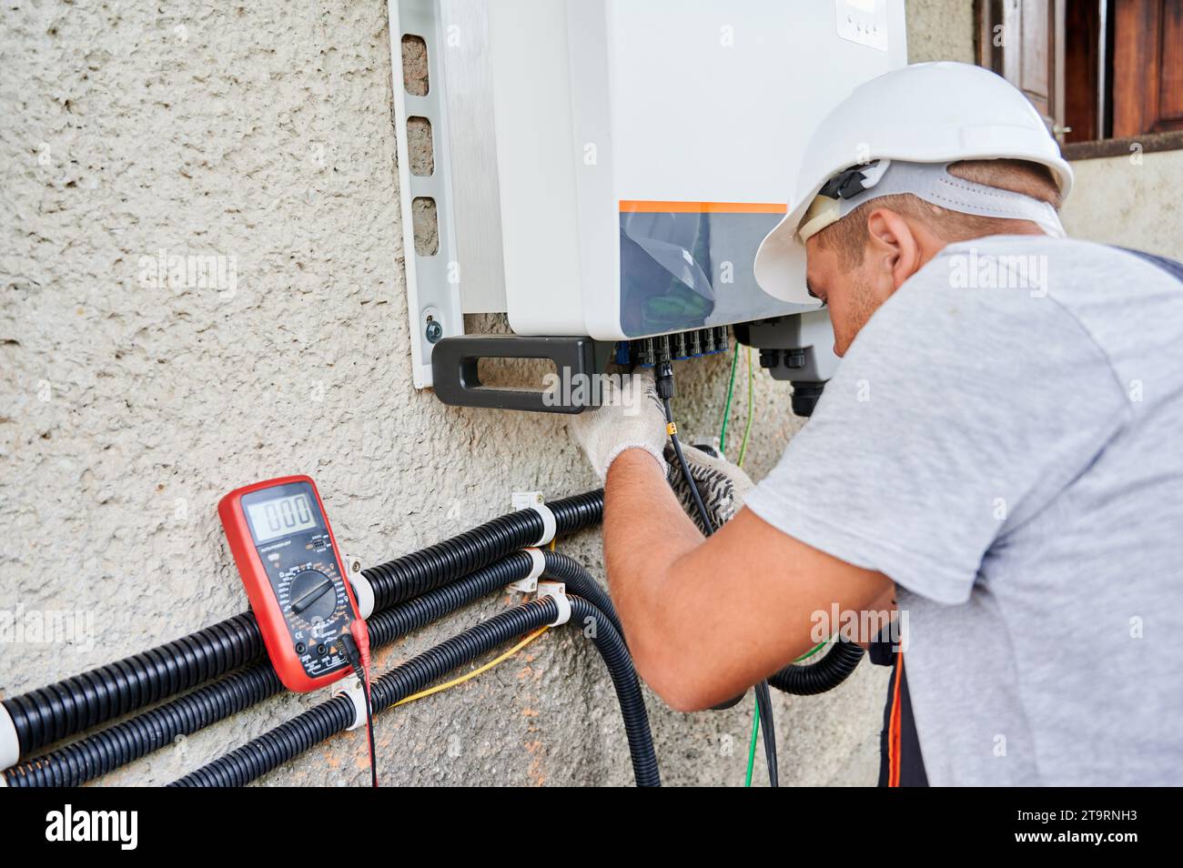 Man electrician installing solar panel system. Technician in helmet and ...