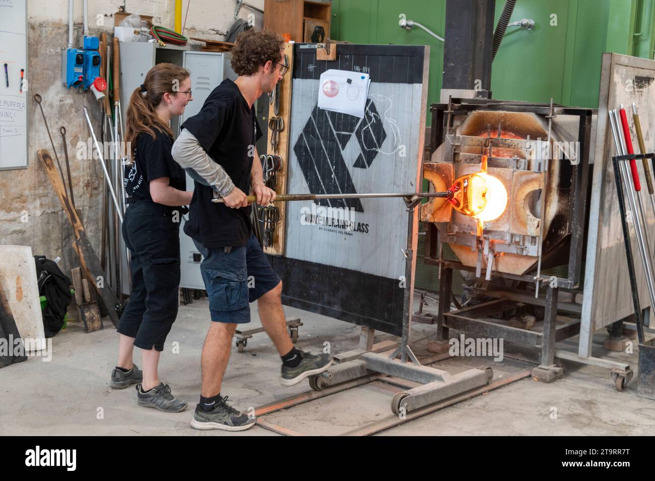 A large clear glass vase being heated in one of the furnaces by a ...